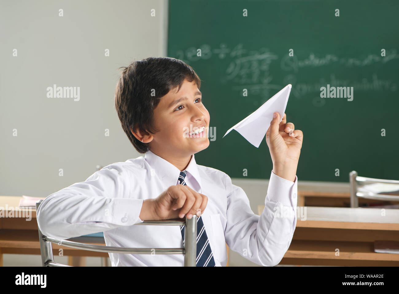 Schoolboy playing with paper plane in classroom Stock Photo - Alamy