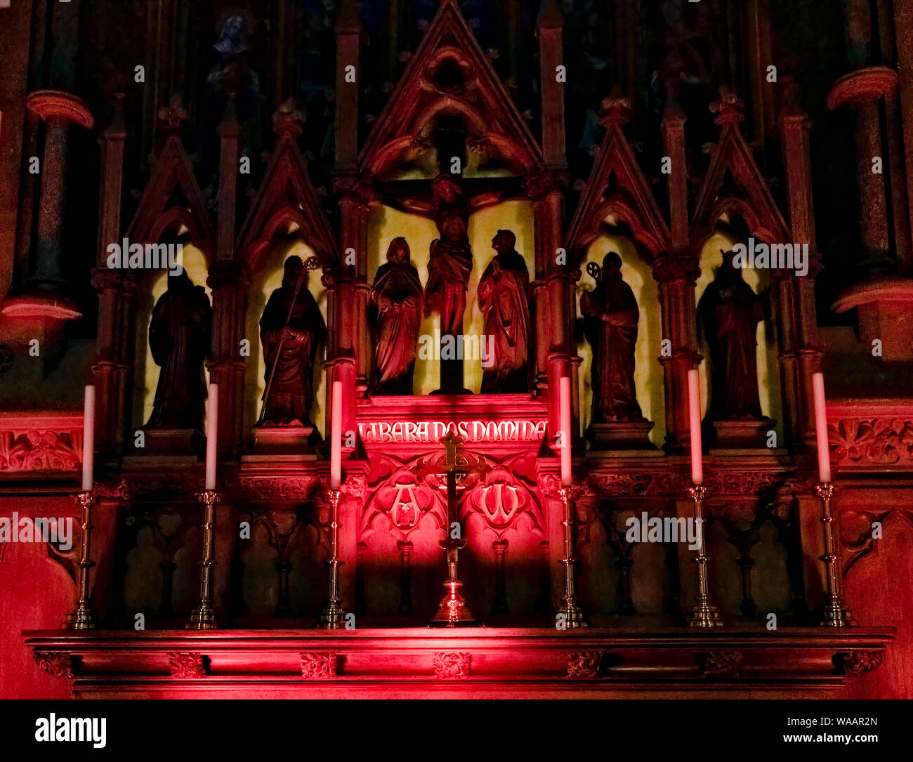 A church altar with statues of the saints, candles and a carved Latin ...