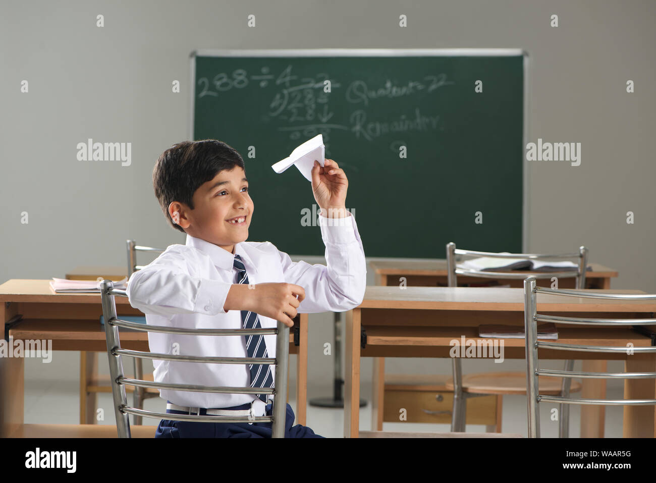 Schoolboy playing with paper plane in classroom Stock Photo - Alamy