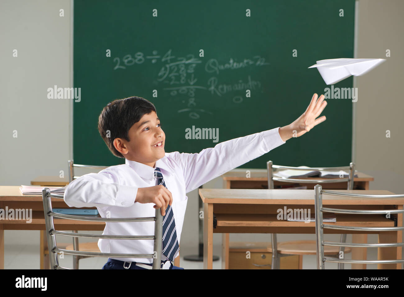 Schoolboy playing with paper plane in classroom Stock Photo - Alamy