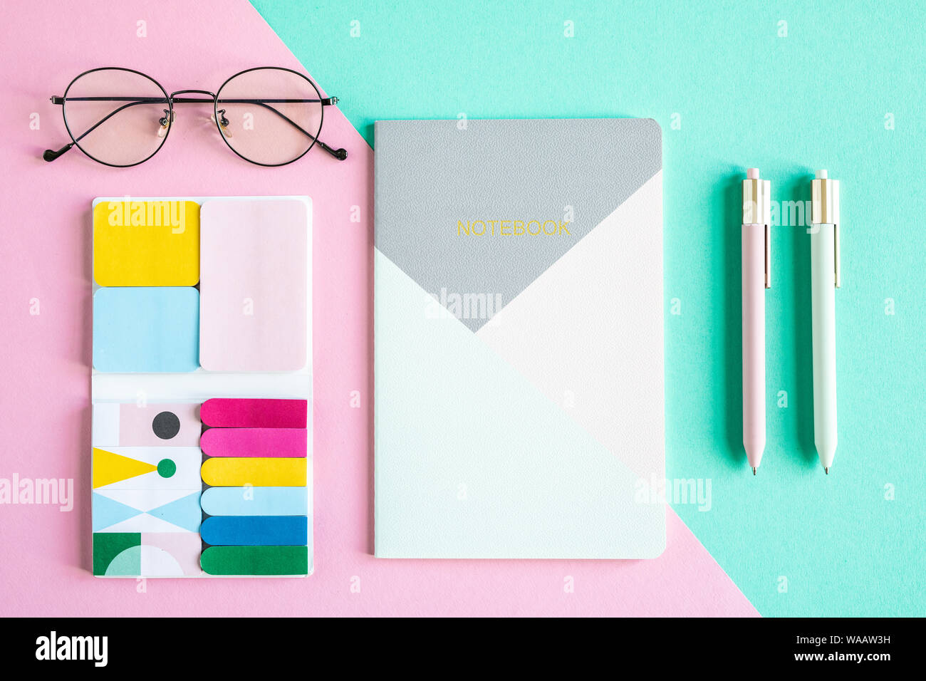 Overview of notebook, two pens, eyeglasses and set of office supplies ...