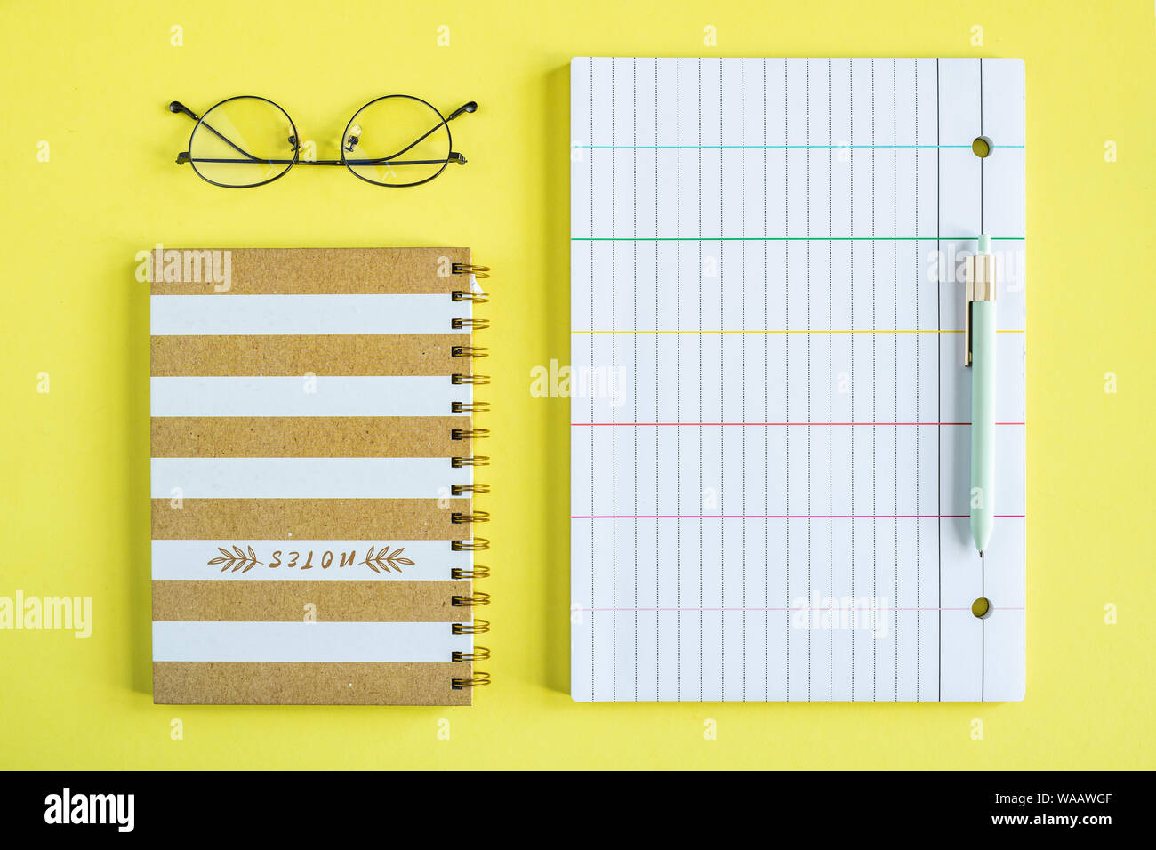 Eyeglasses, closed notebook with spiral binder, pen and lined paper ...