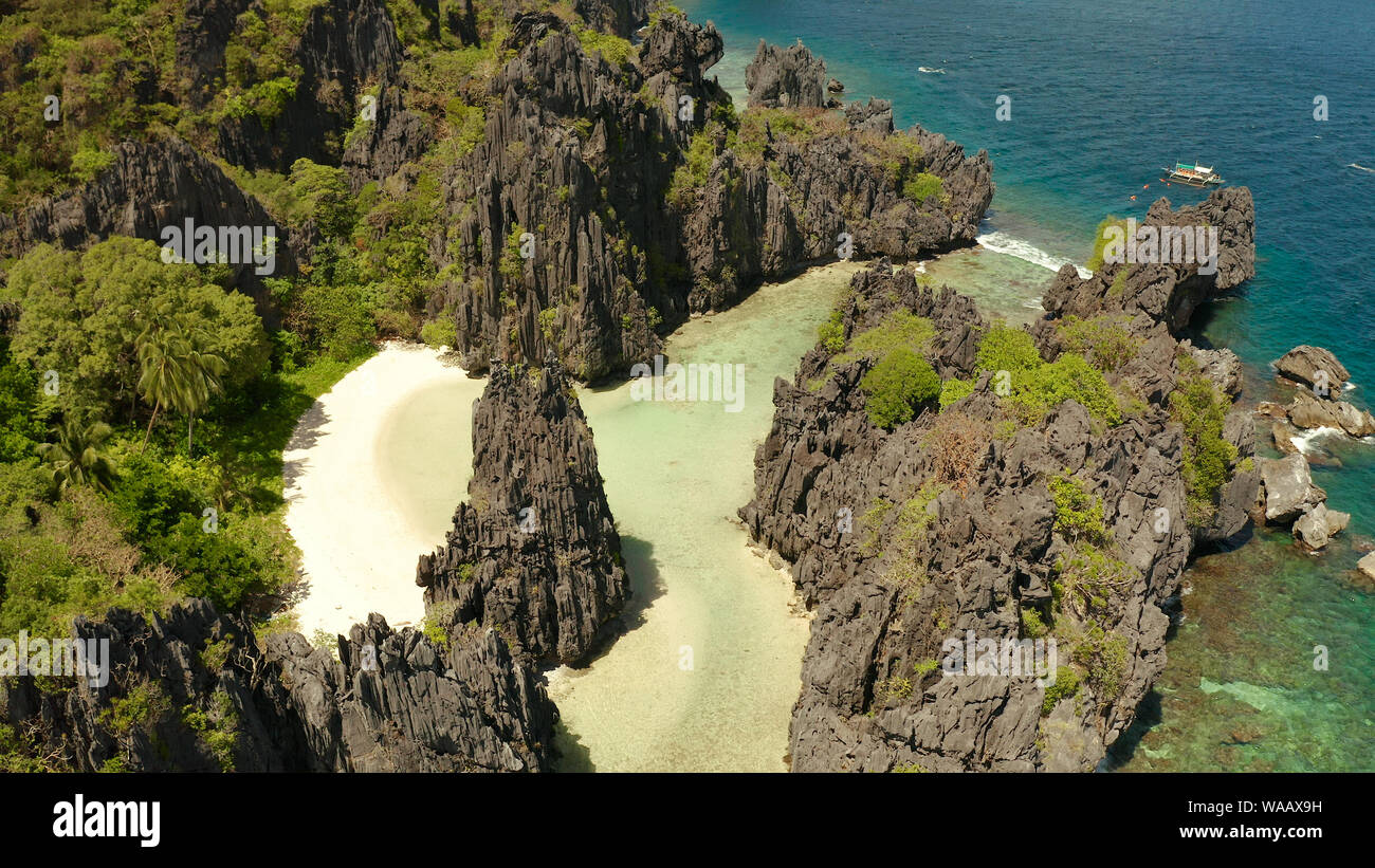 Tropical lagoon with sandy beach surrounded by cliffs. El nido ...