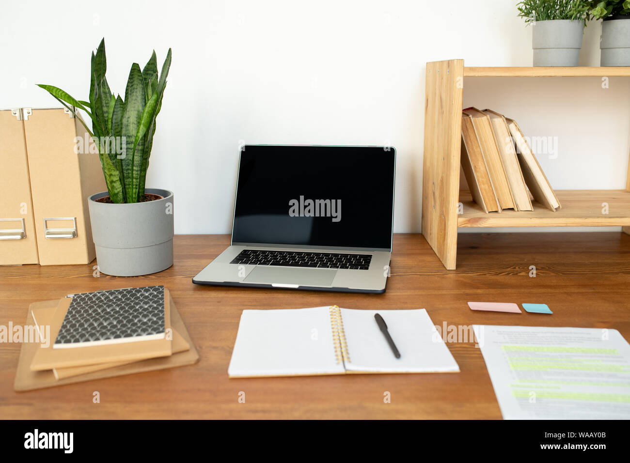 Wooden shelf with books, open copybook with pen, laptop and stack of ...