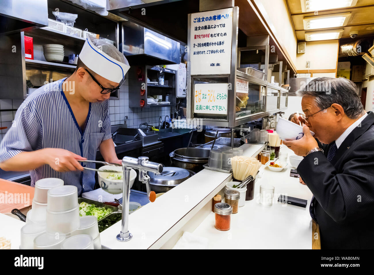 Typical interior view showing cook and customer eating noodles hi-res ...