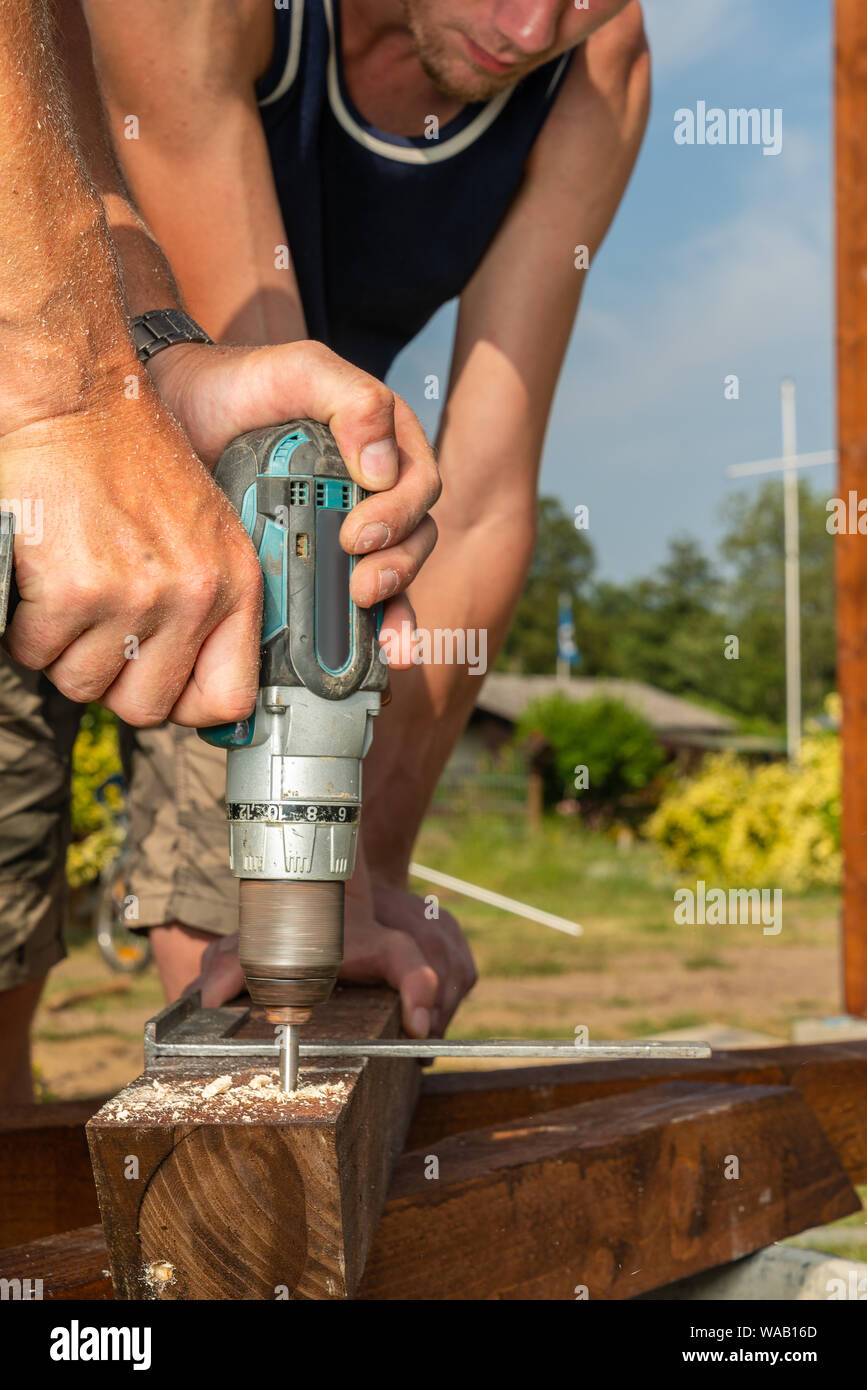 a carpenter drills hole into timber wtih cordless screwdriver Stock ...