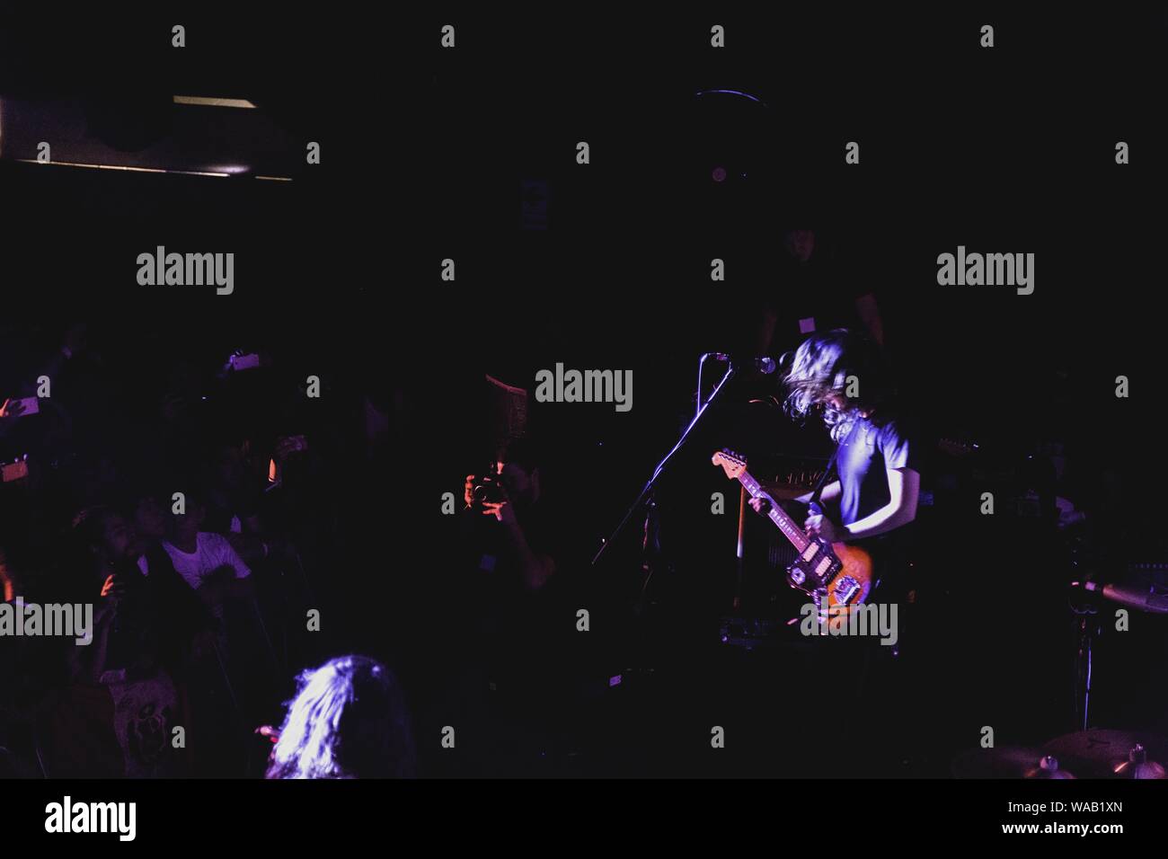 Crowd at a concert having fun with a band playing rock music on stage ...