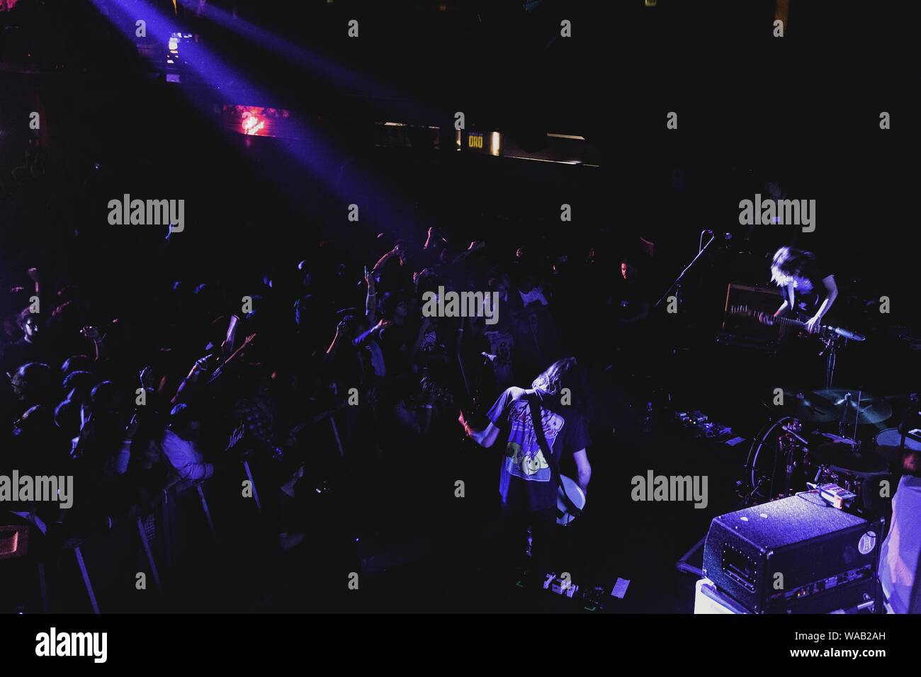 Crowd at a concert having fun with a band playing rock music on stage ...
