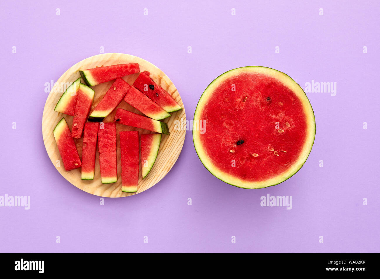 Watermelon cut in half and slices isolated in violet portage background ...
