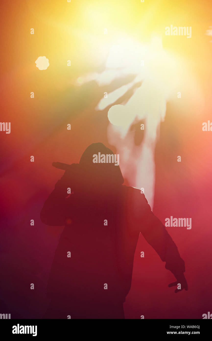 Rap singer with mic on stage in bright red and yellow lights.Silhouette ...