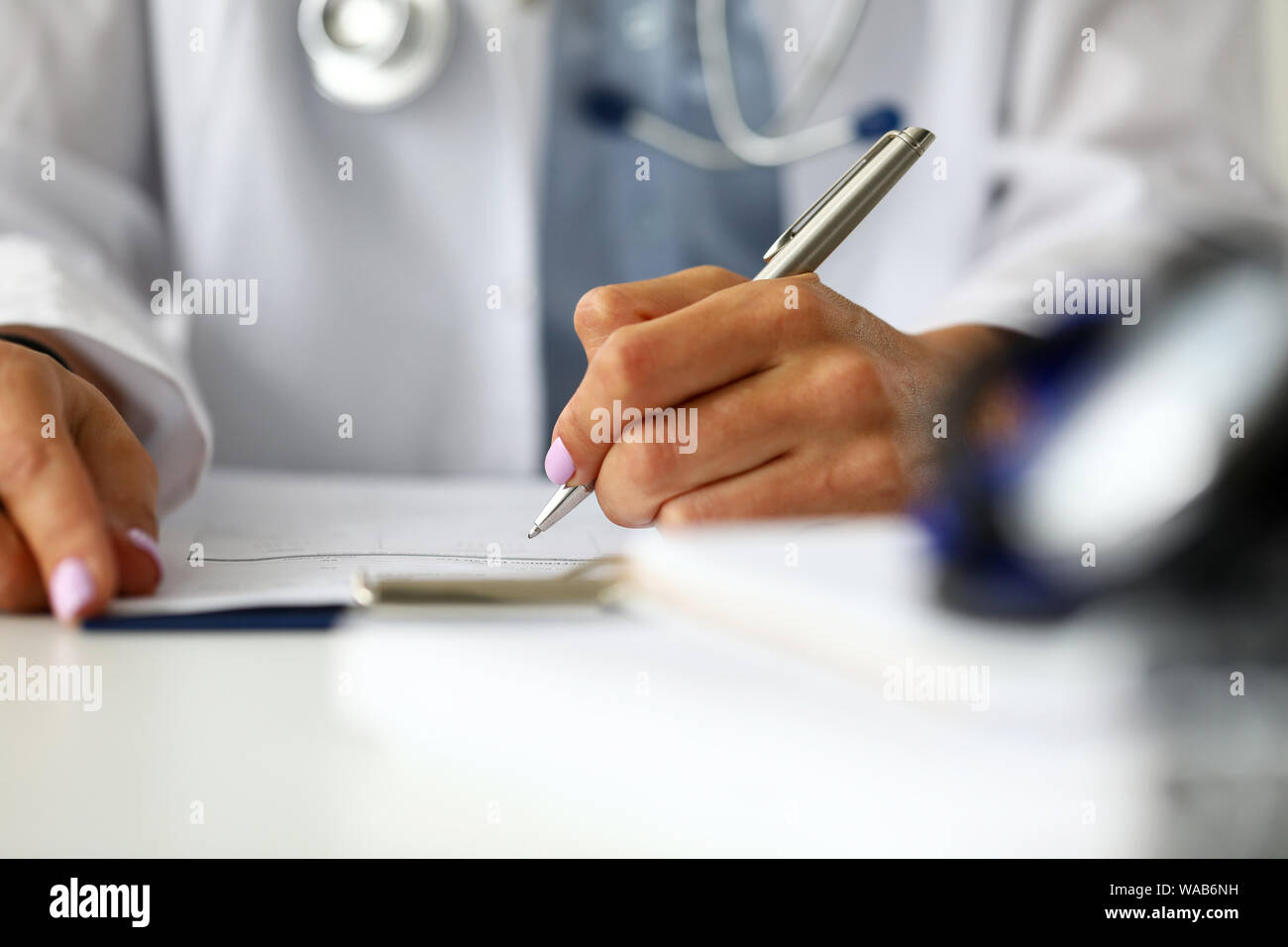 Arms of GP writing with silver pen document Stock Photo - Alamy