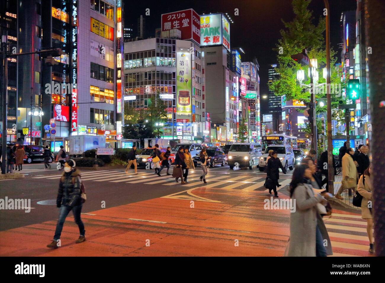 TOKYO, JAPAN - NOVEMBER 30, 2016: People walk under the neon lights of ...
