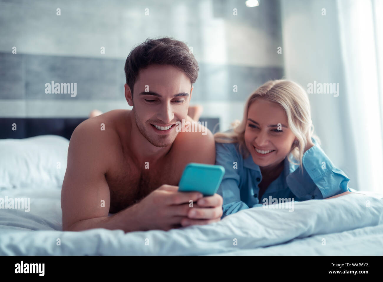 Couple laughing while watching funny video chilling in bed Stock Photo ...