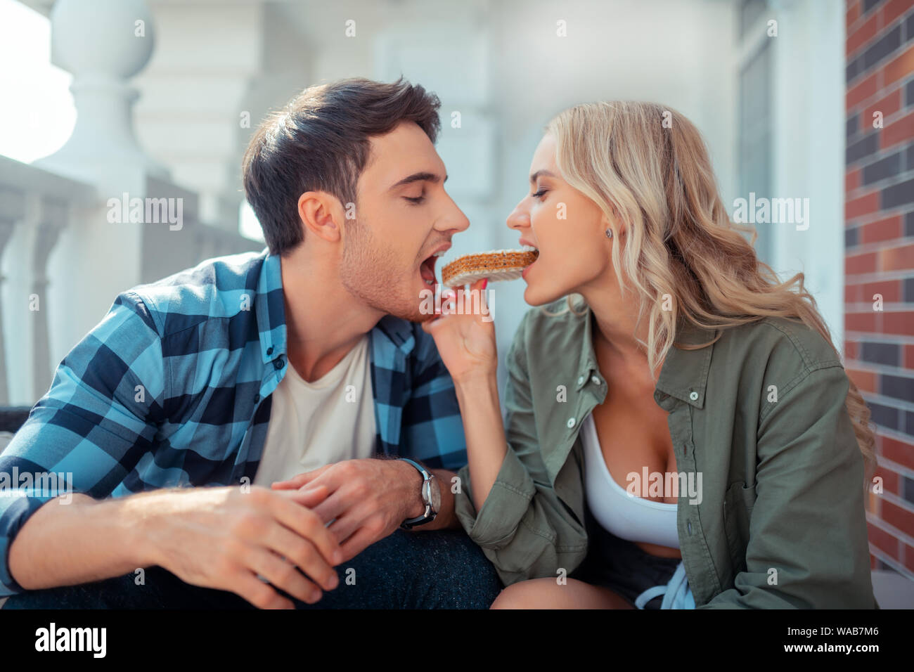 Couple eating wafer together while enjoying breakfast outside Stock ...