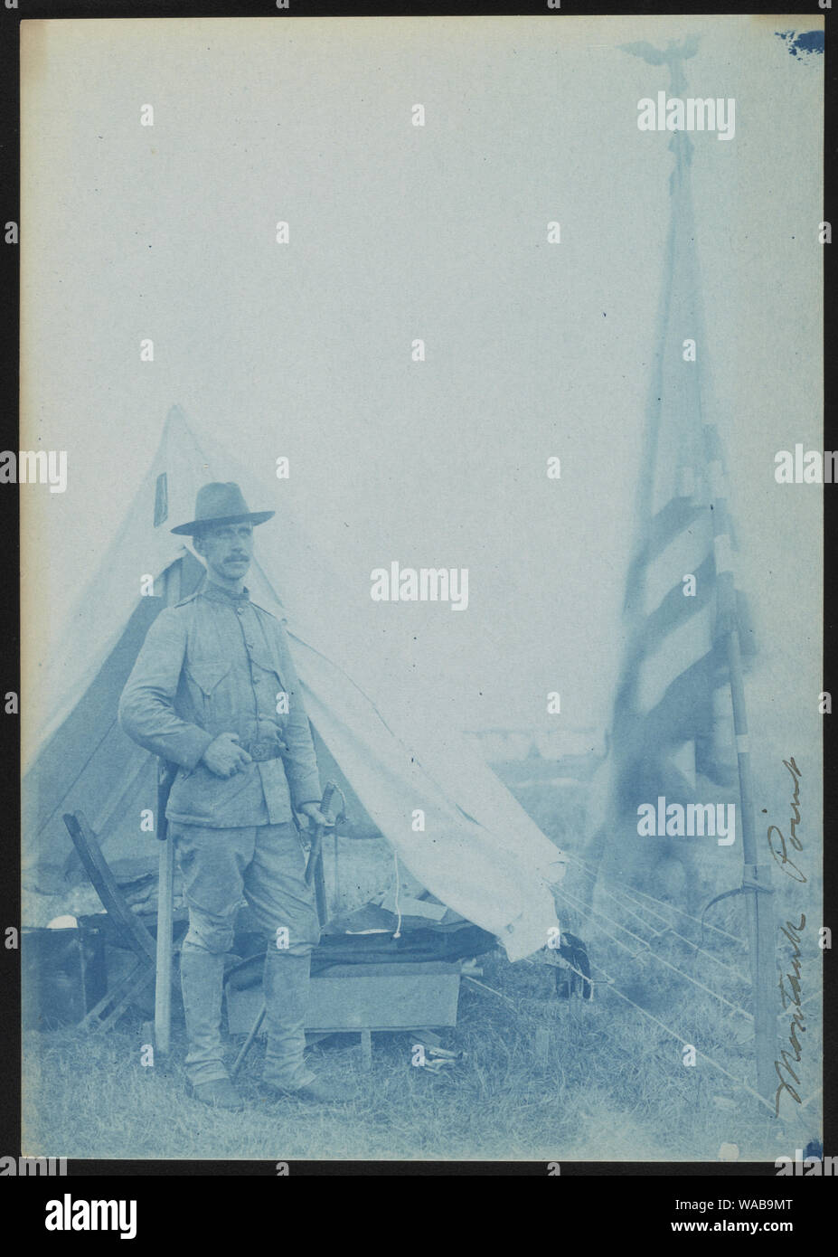 Colonel George Herbert Harries, standing near tent at the Rough Riders ...