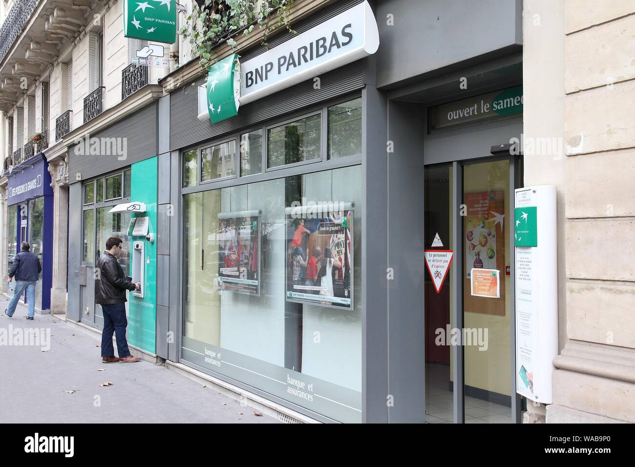 PARIS, FRANCE - JULY 23, 2011: Person visits BNP Paribas Bank branch in ...