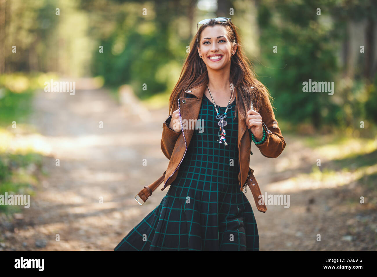 Happy smiling woman is walking along forest path and enjoying landscape ...