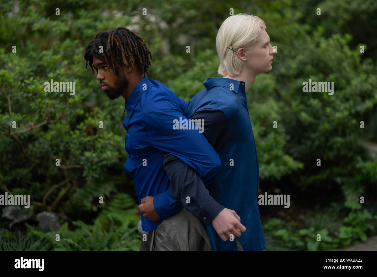 Two men with different skin color standing near plants Stock Photo - Alamy