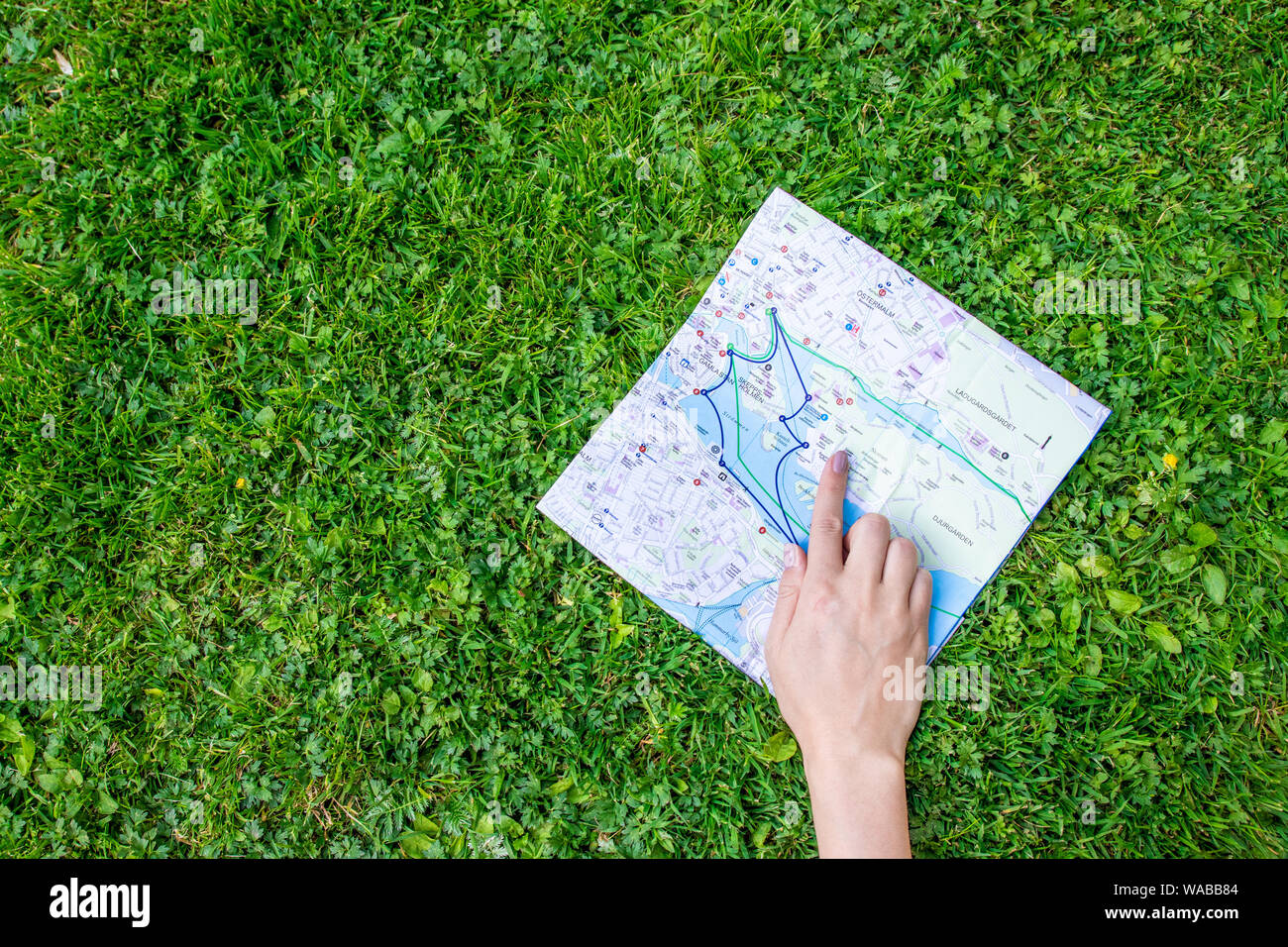 Woman hand holding a paper sheet with the travel map over green forest ...