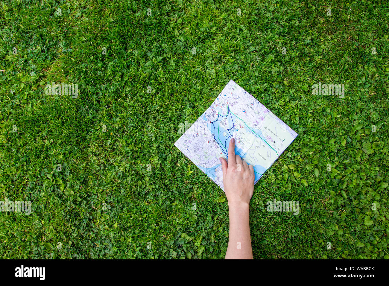 Female hand shows a finger on a topographic map on the grass Stock ...