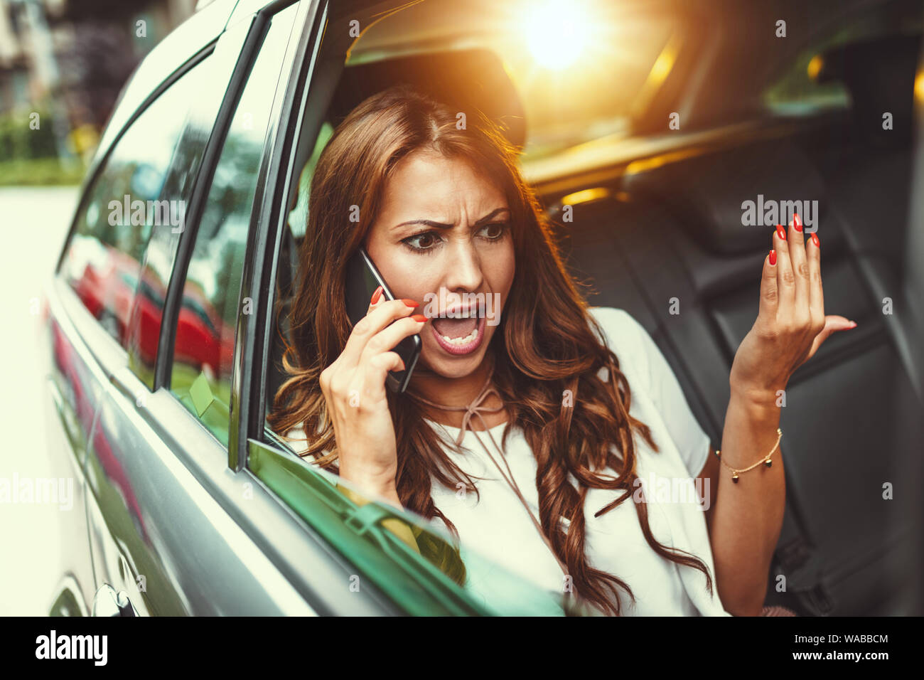 Young angry business woman is holding smartphone in her hand and argues ...