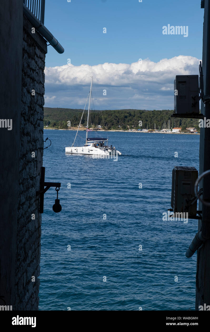 Yacht moving in sea as seen through buildings, Rovinj, Istria, Croatia ...