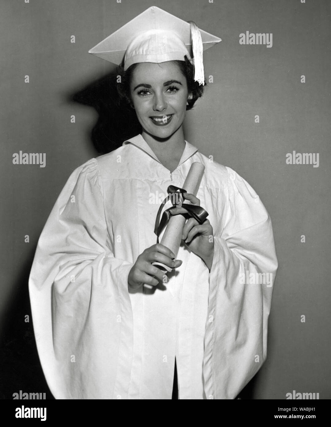 Elizabeth Taylor in a cap and Gown and holding her diploma after ...