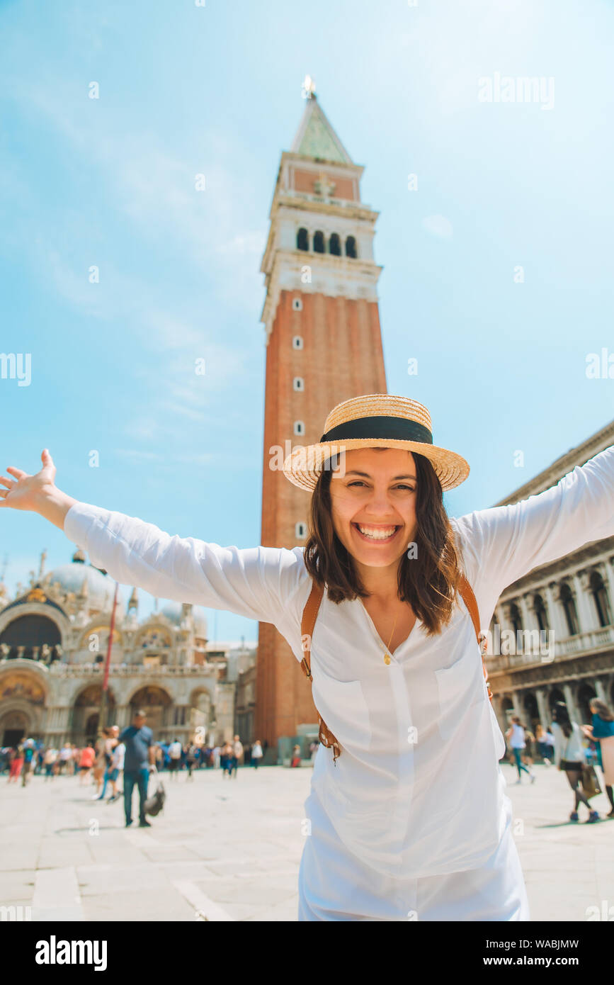 smiling pretty caucasian woman rise up hands at venice city square bell ...