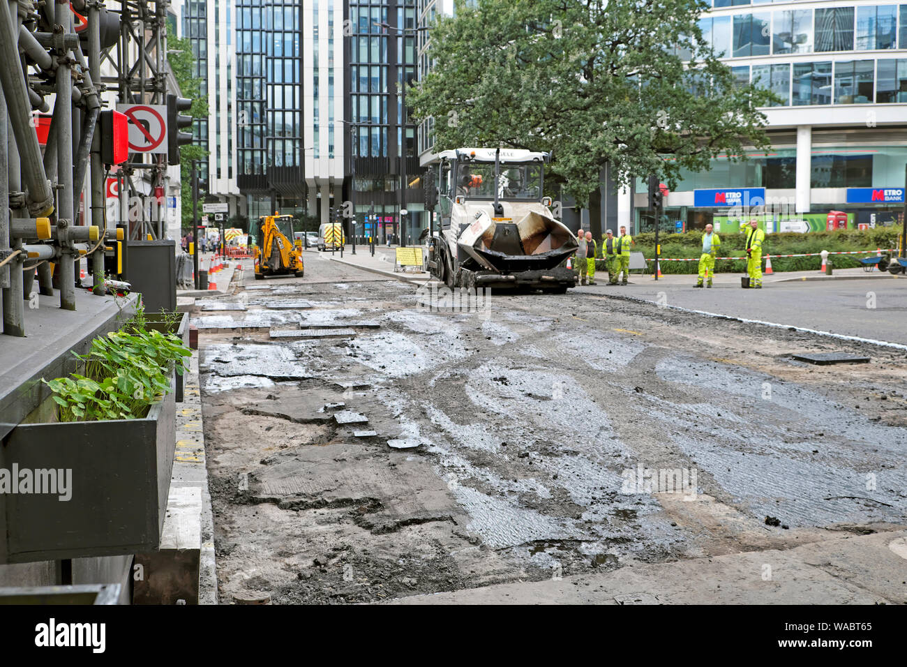 Road repair workers resurfacing street with tarmac at London Wall and ...