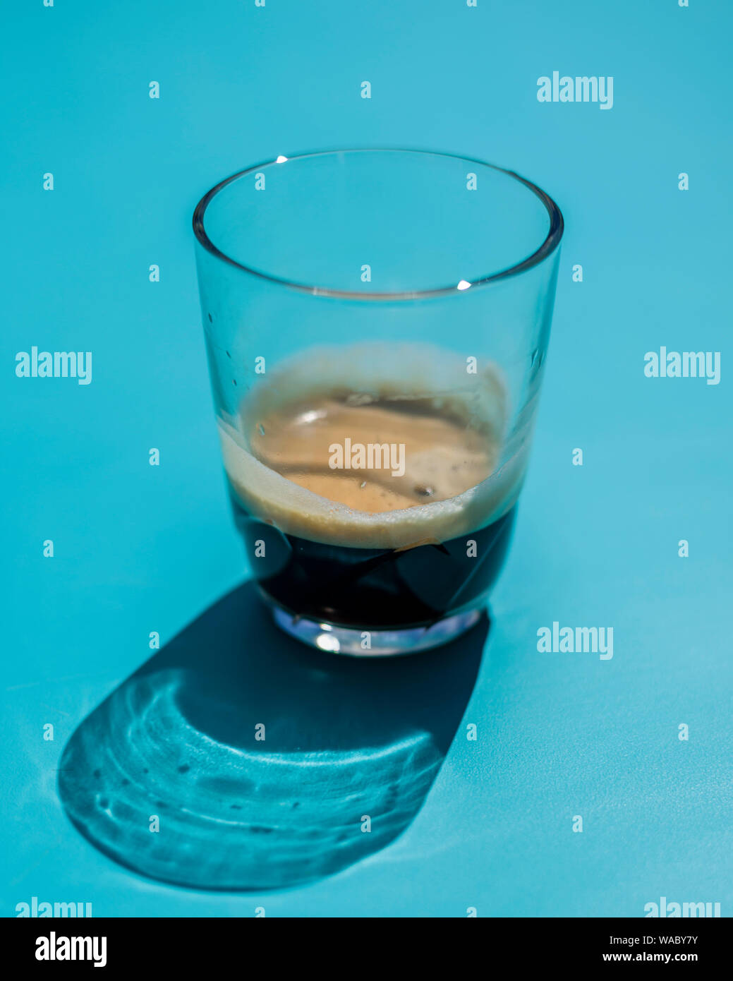 Small glass of black coffee on a blue table Stock Photo - Alamy