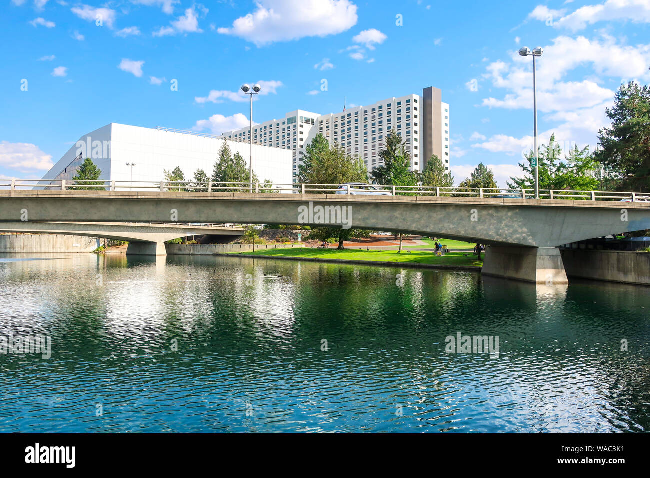 A modern city office building rises behind a bridge over a park and ...
