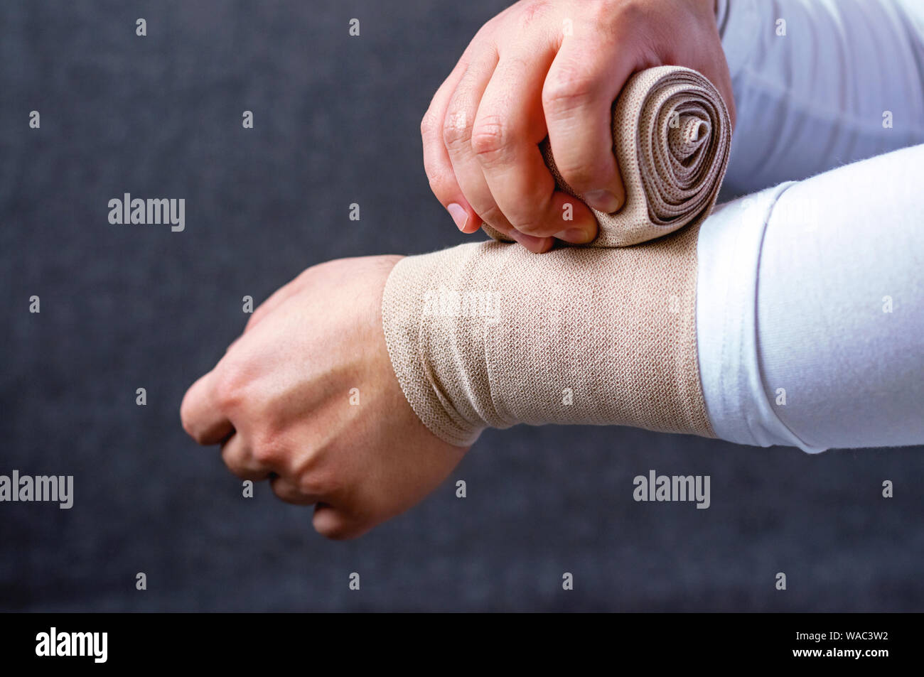A man bandages his hand with a sports bandage. Injuries and strains in ...
