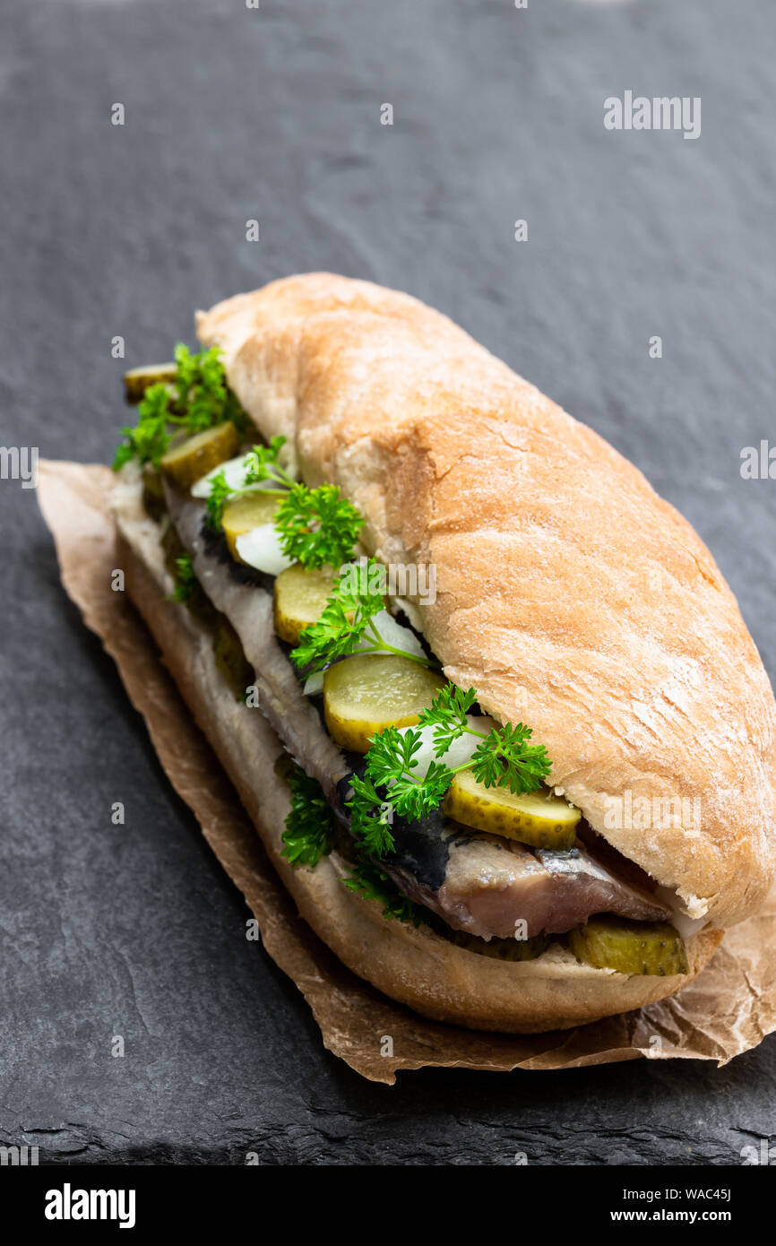 Traditional Dutch sandwich with herring and pickles on black stone ...
