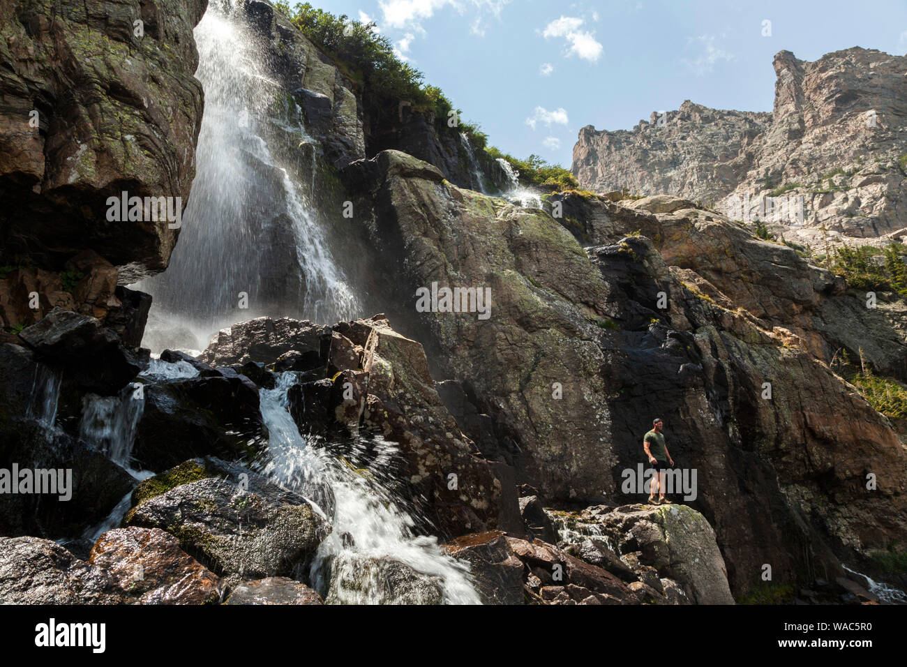 A man poses below Timberline Falls, Rocky Mountain National Park ...