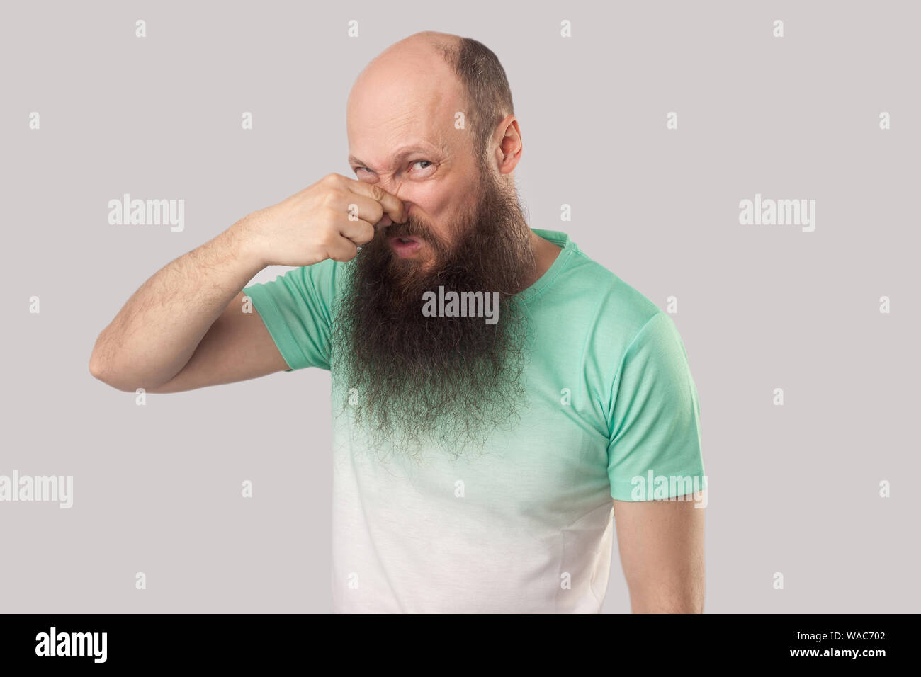 Bad smell. Portrait of confused middle aged bald man with long beard in ...