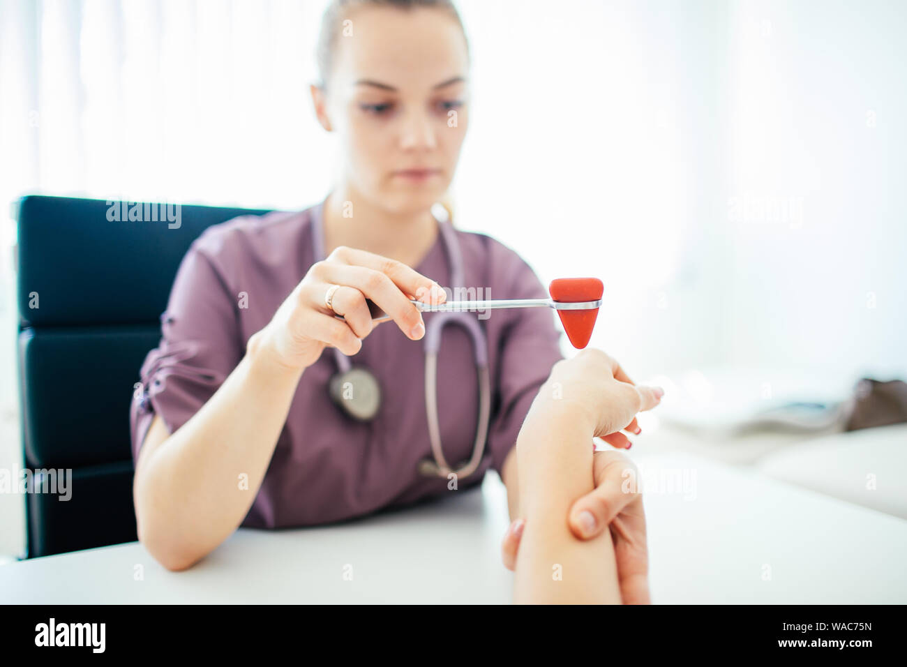 Neurological examination. The neurologist testing hand reflexes on a ...