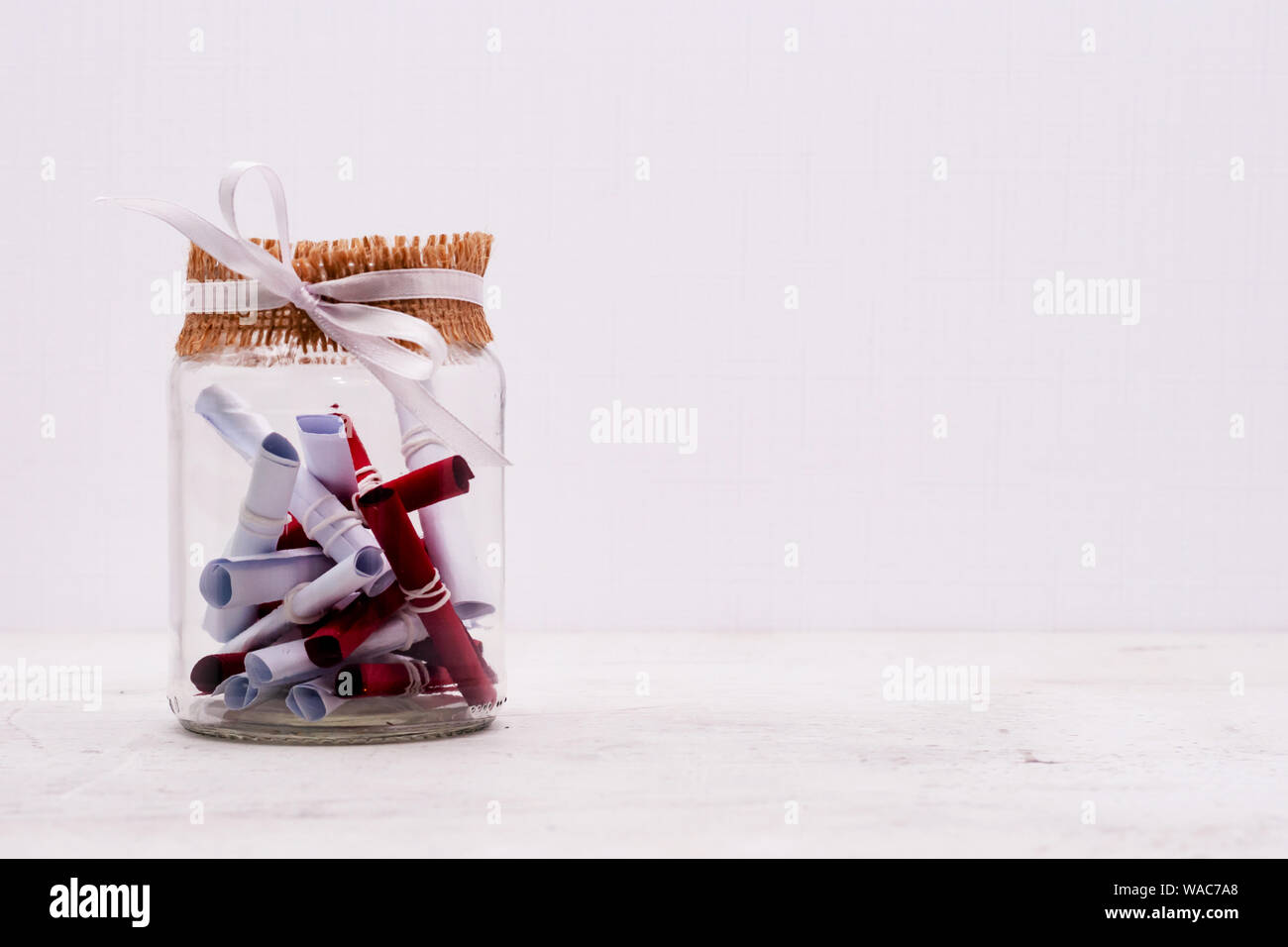 A glass jar with colored notes of craft paper. Light background Stock ...