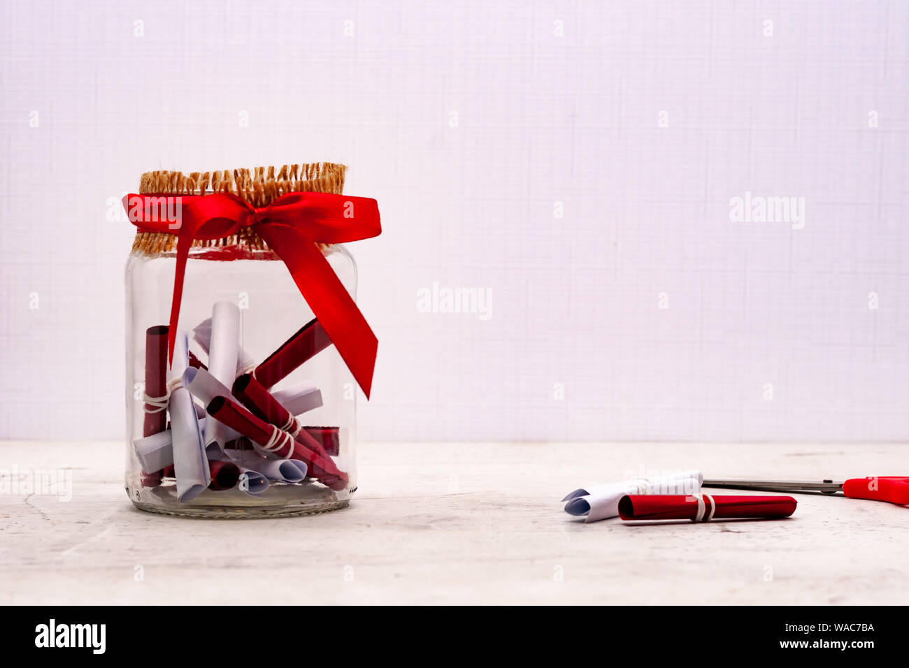 A glass jar with notes of craft paper. Light background Stock Photo - Alamy