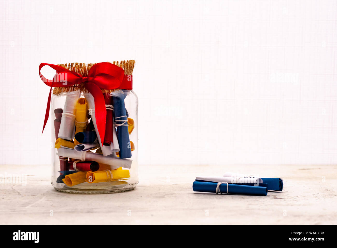 A glass jar with notes of craft paper. Light background Stock Photo - Alamy