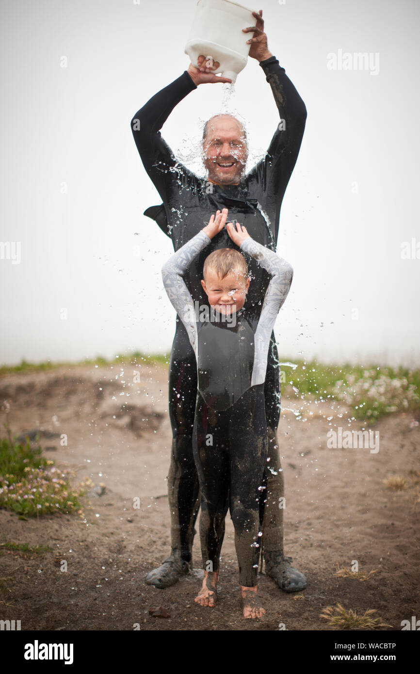 Portrait of a mid adult man pouring water over his son while at the ...