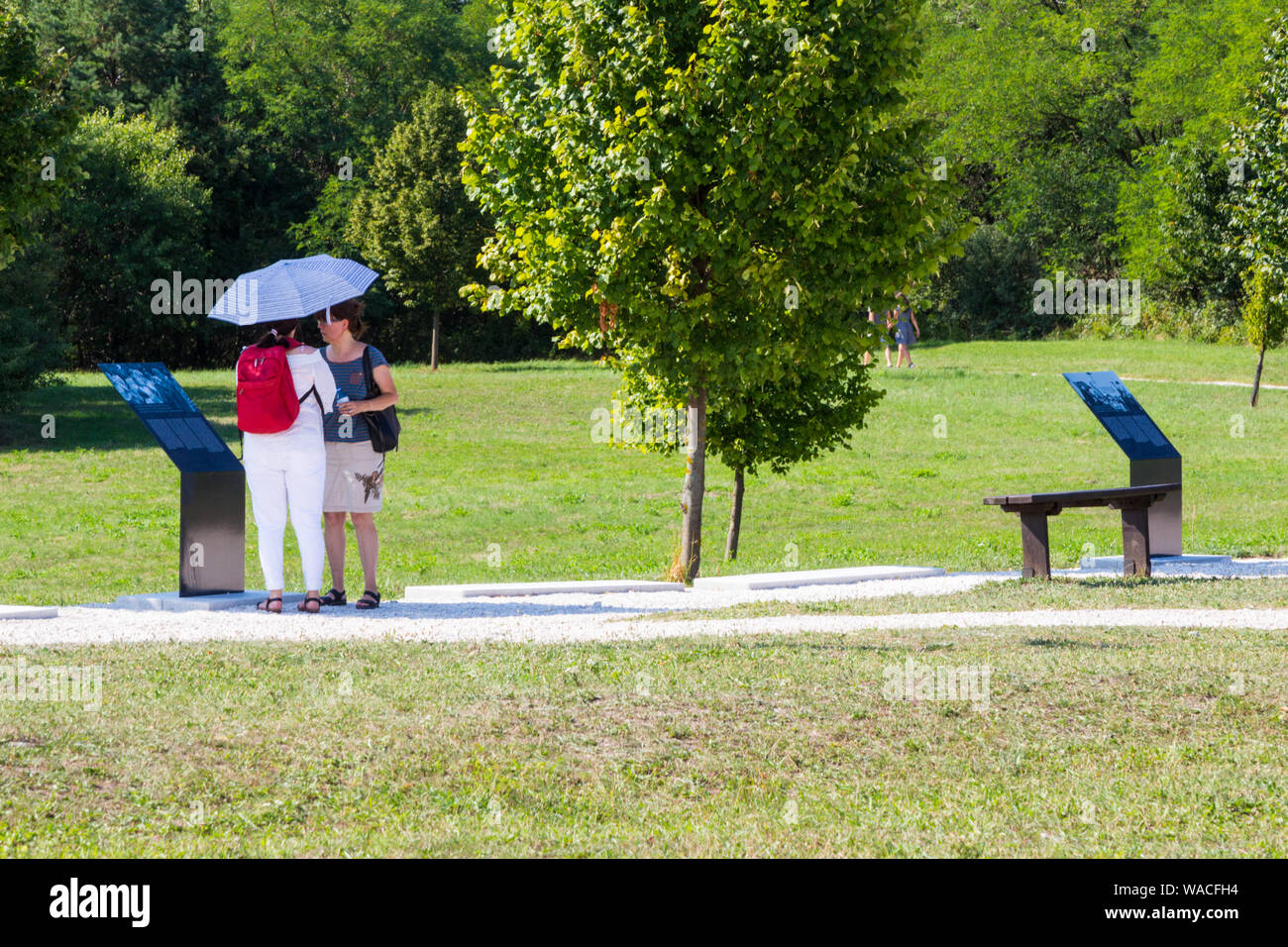 Two women with umbrella observing the outdoor history path exhibition ...