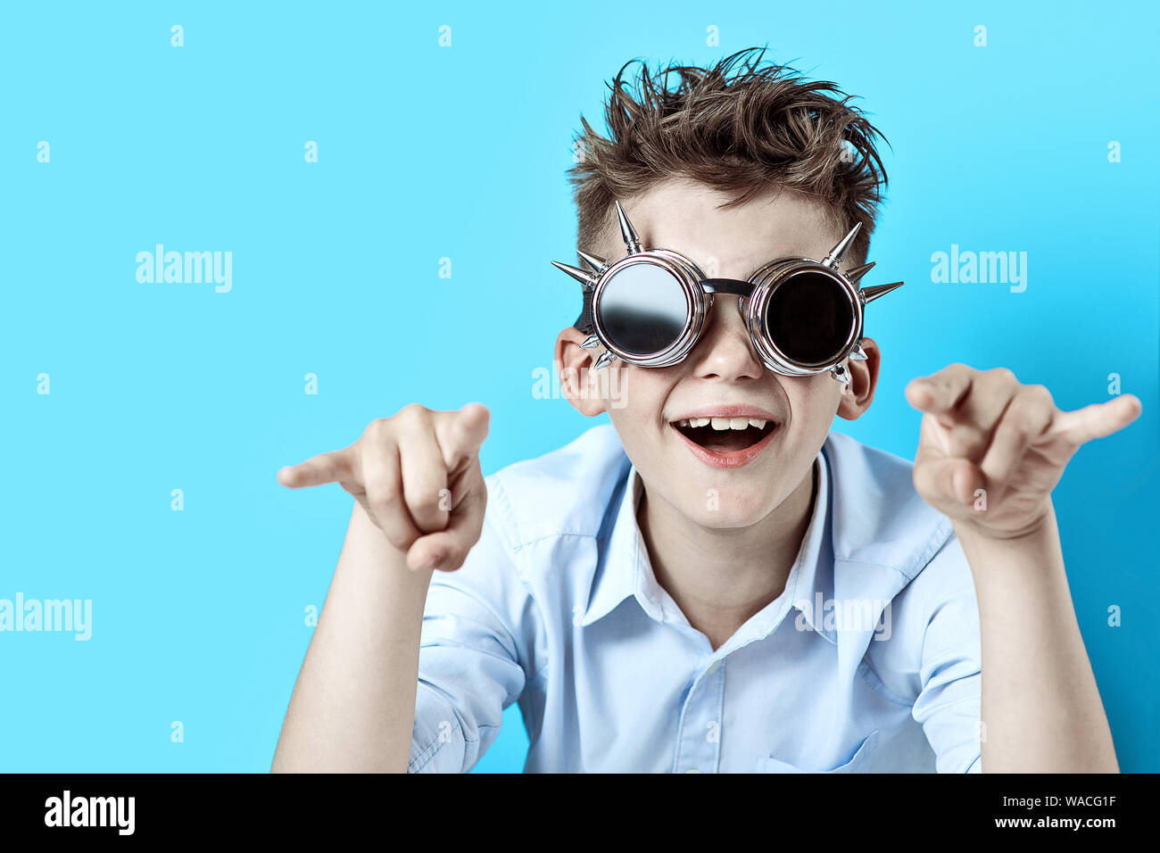 rocker boy in blue shirt and biker glasses on light blue background ...