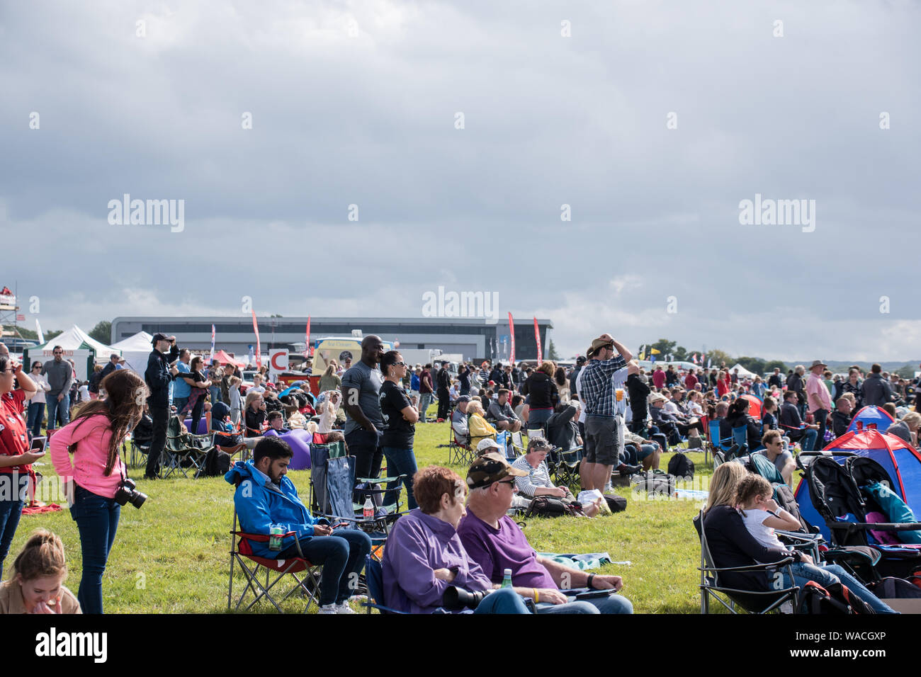 Large crowd of people in open ground looking at airshow display ...