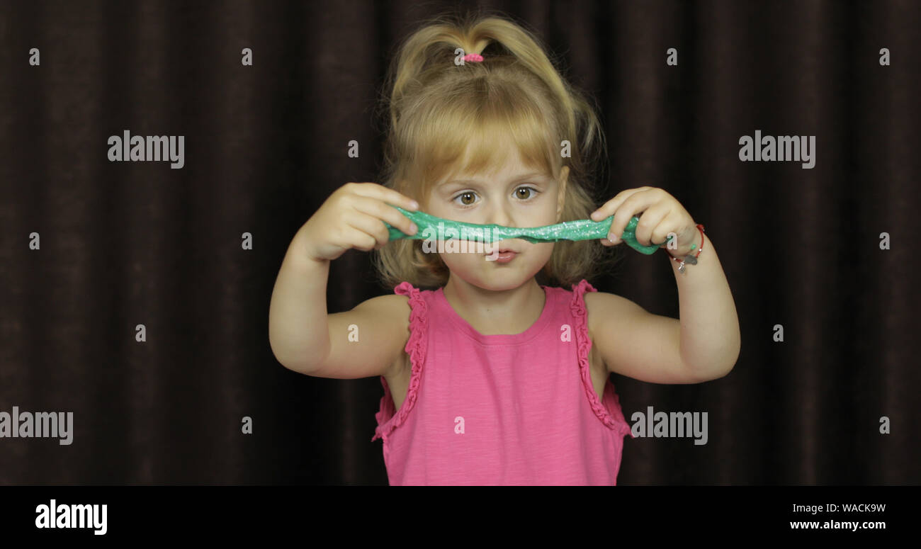 Child having fun making green slime. Kid playing with hand made toy ...
