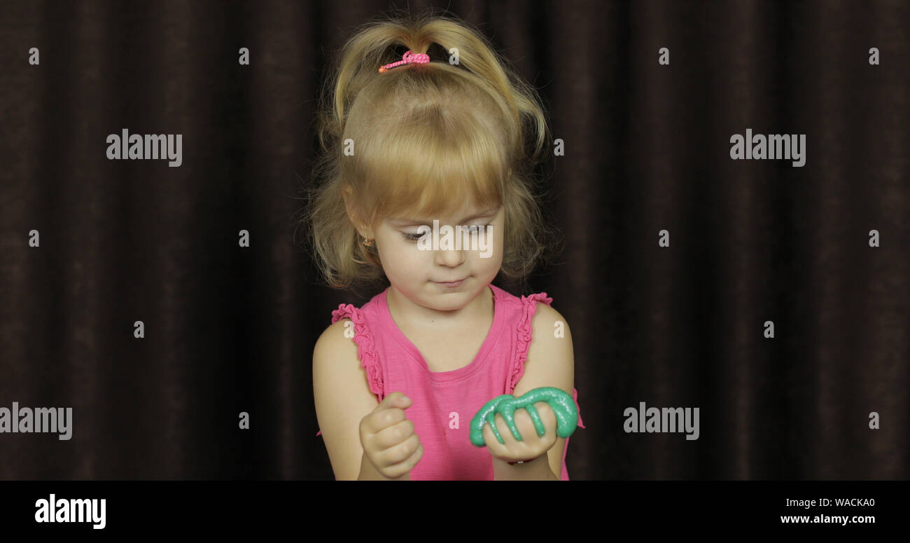 Child having fun making green slime. Kid playing with hand made toy ...