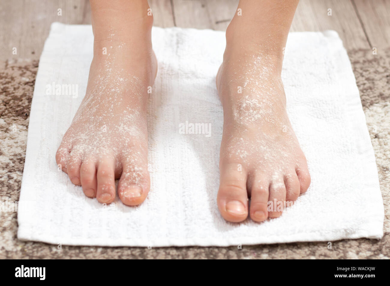 Children's feet covered with white powder lie on a white towel. Talc on ...