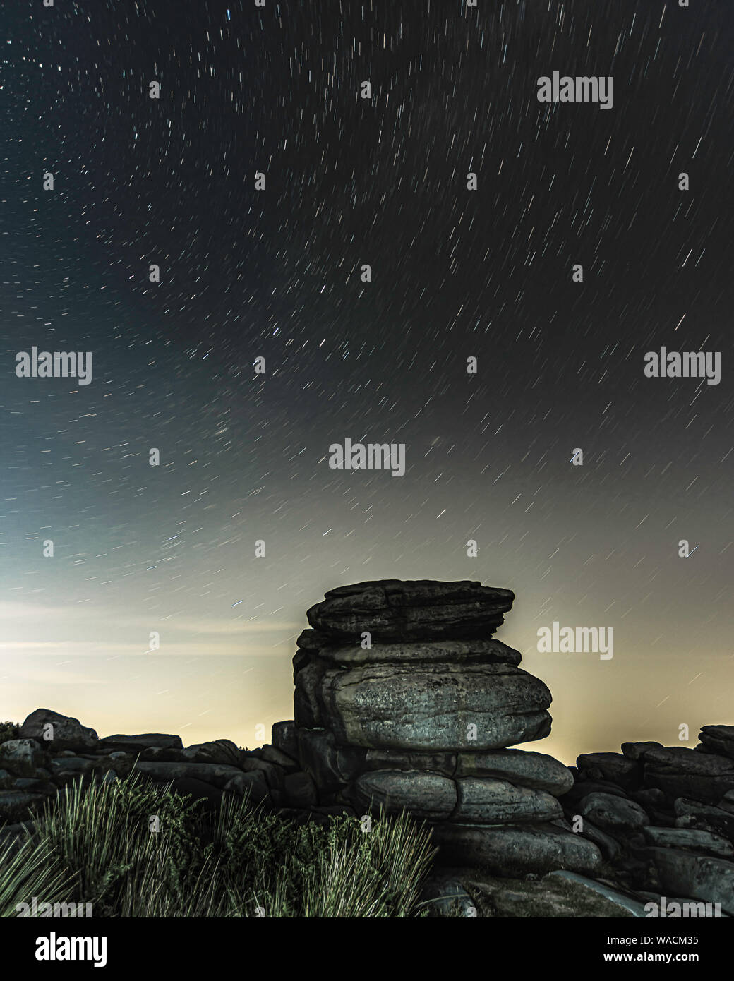 Sky full of stars over rocky hill in Peak District,UK.Star trials and ...
