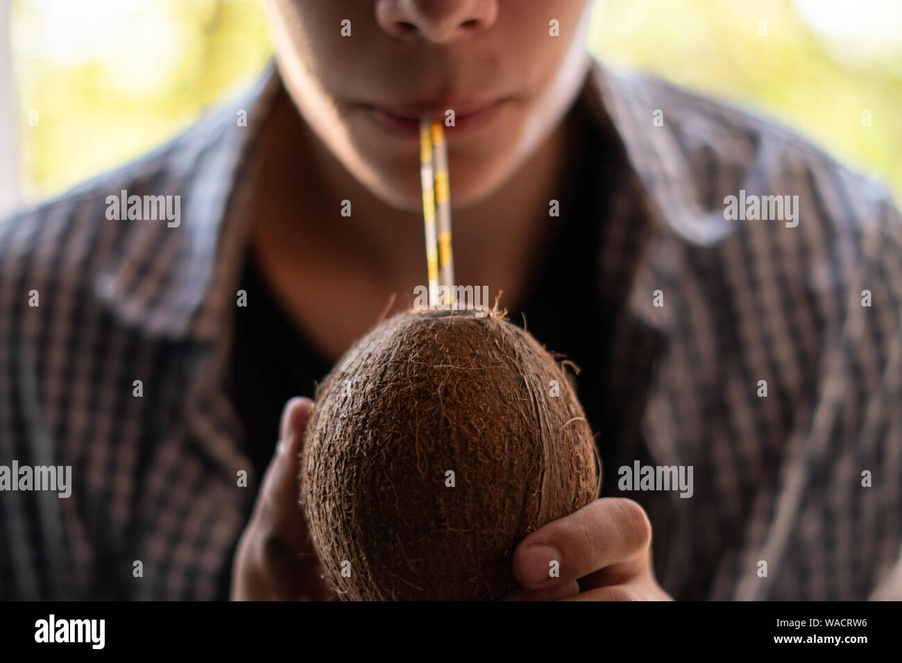 young man holding a coconut with a straw and drinking, close up Stock ...