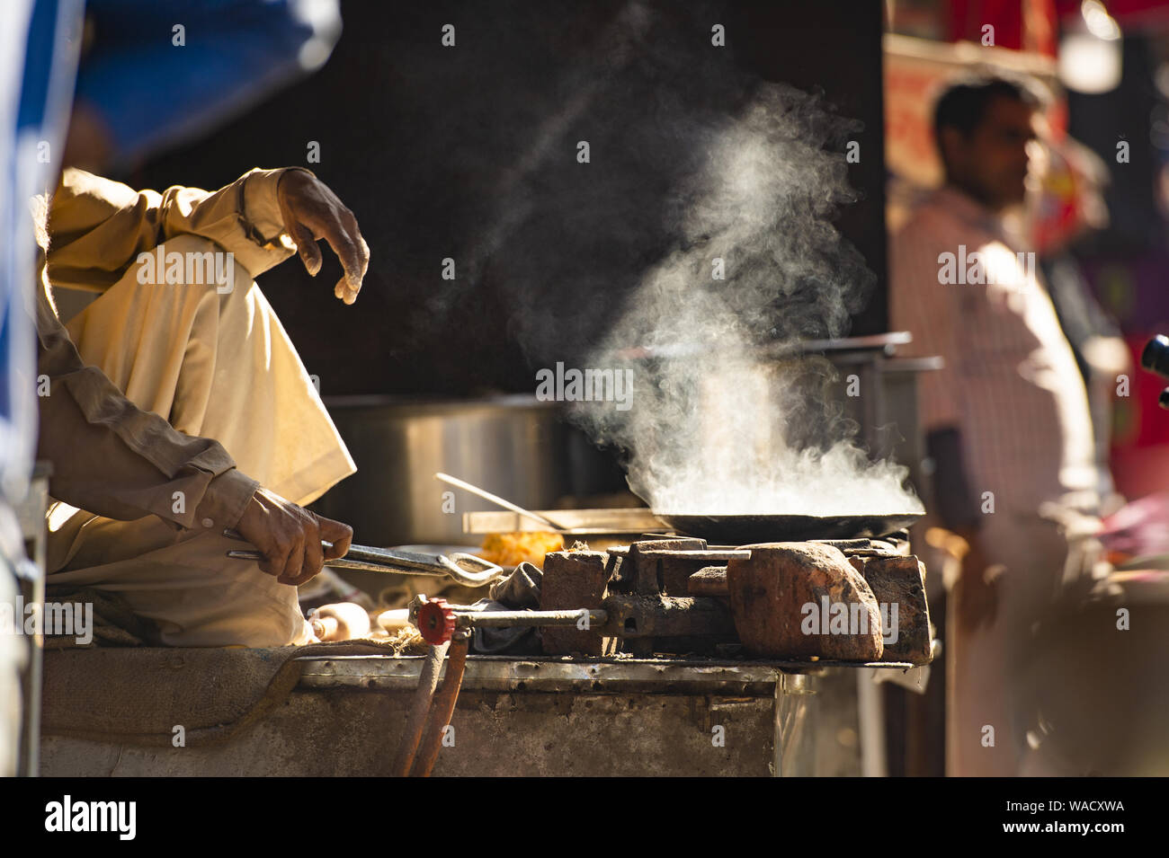 An Indian elderly man is cooking Chapati on the streets of Jaipur ...