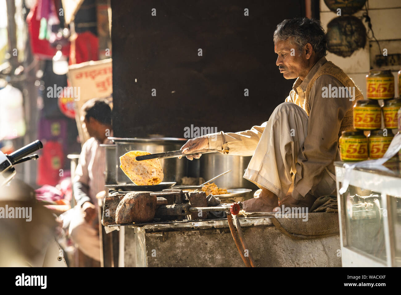 An Indian elderly man is cooking Chapati on the streets of Jaipur ...